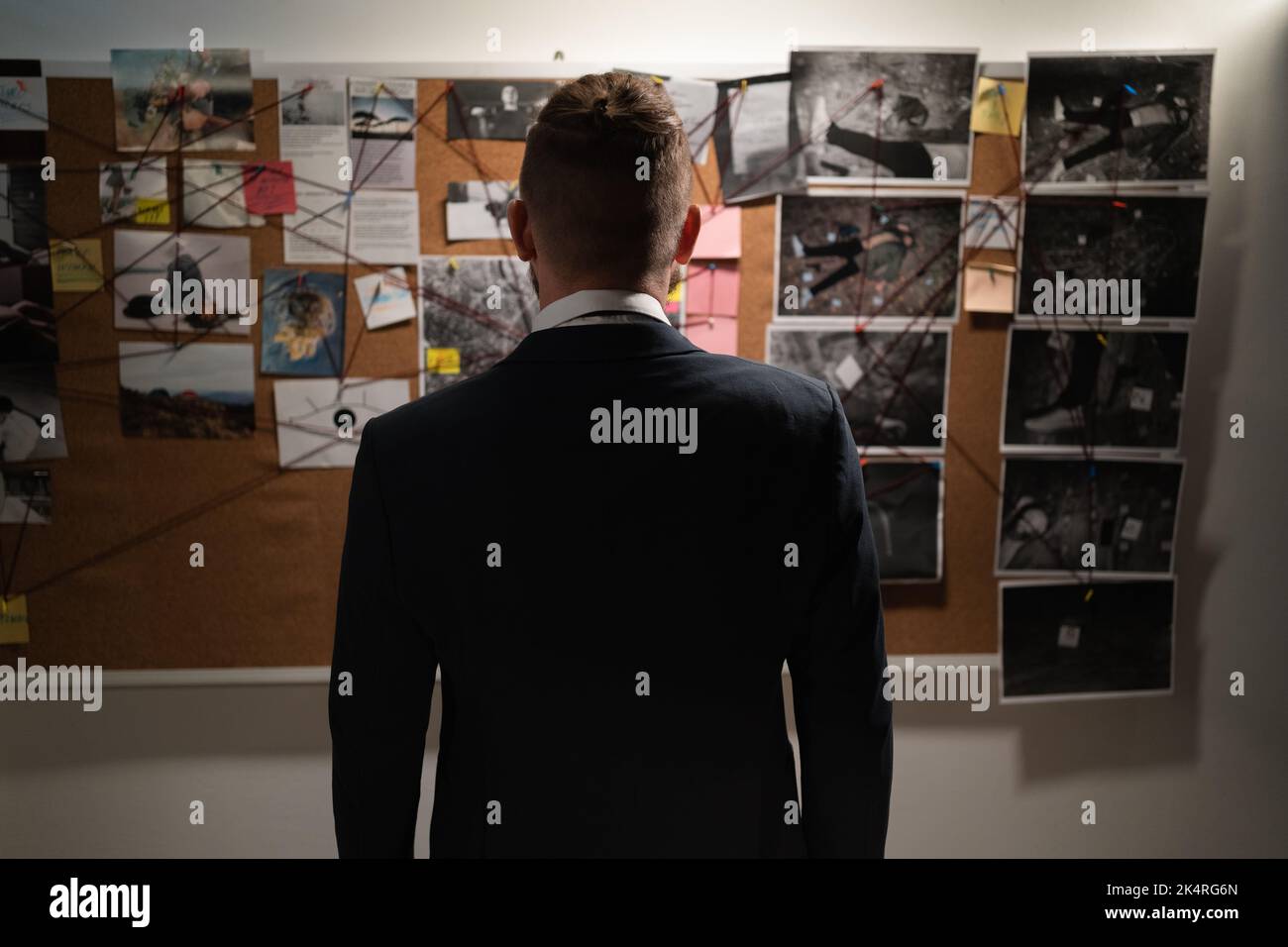 Male detective in the office near the blackboard looking for a killer ...