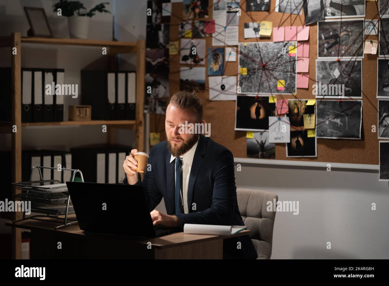 Detective processing evidence in office, working at desk using laptop ...