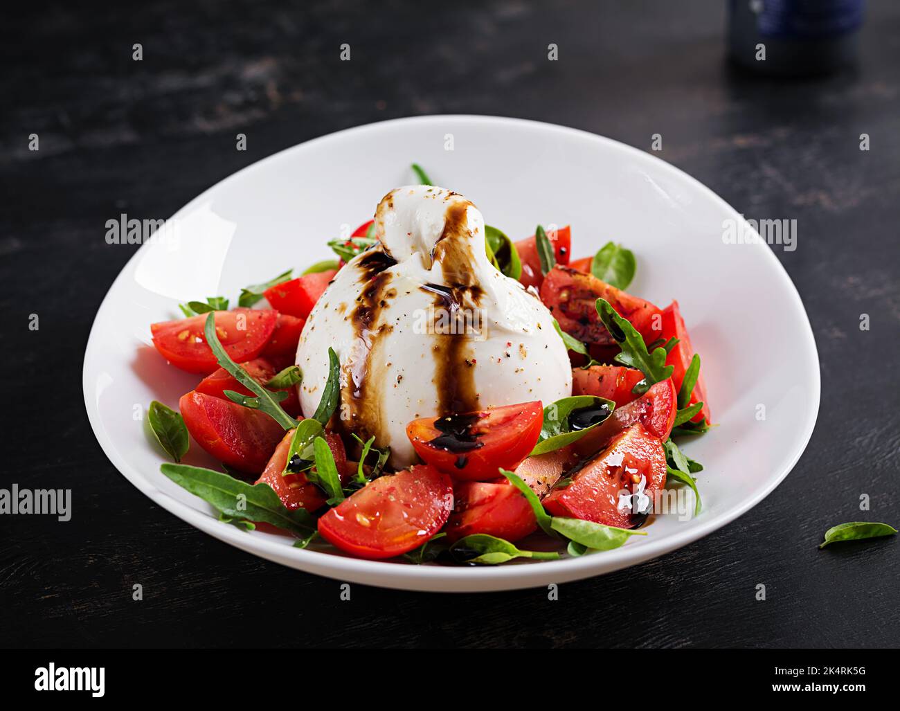 Salad with tomatoes and burrata cheese with basil and olive oil on ...