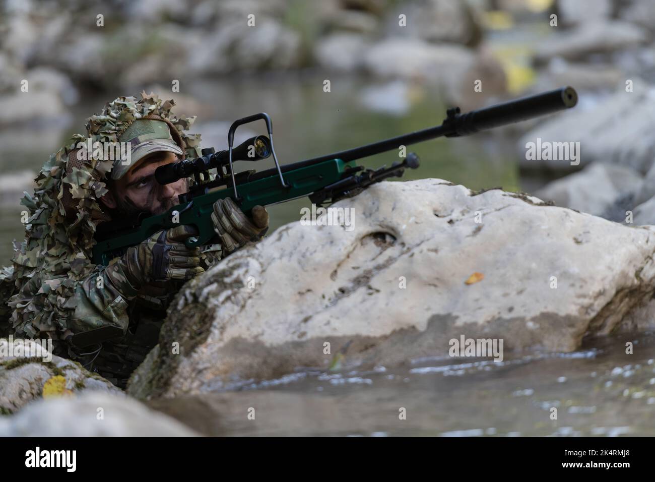 A military man or airsoft player in a camouflage suit sneaking the ...