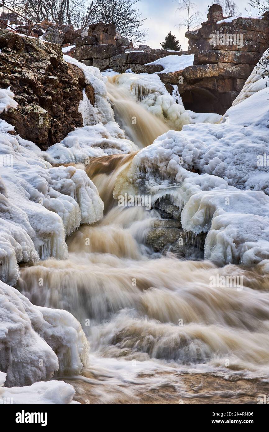 A low exposure of water flowing down the rocks covered in snow Stock ...