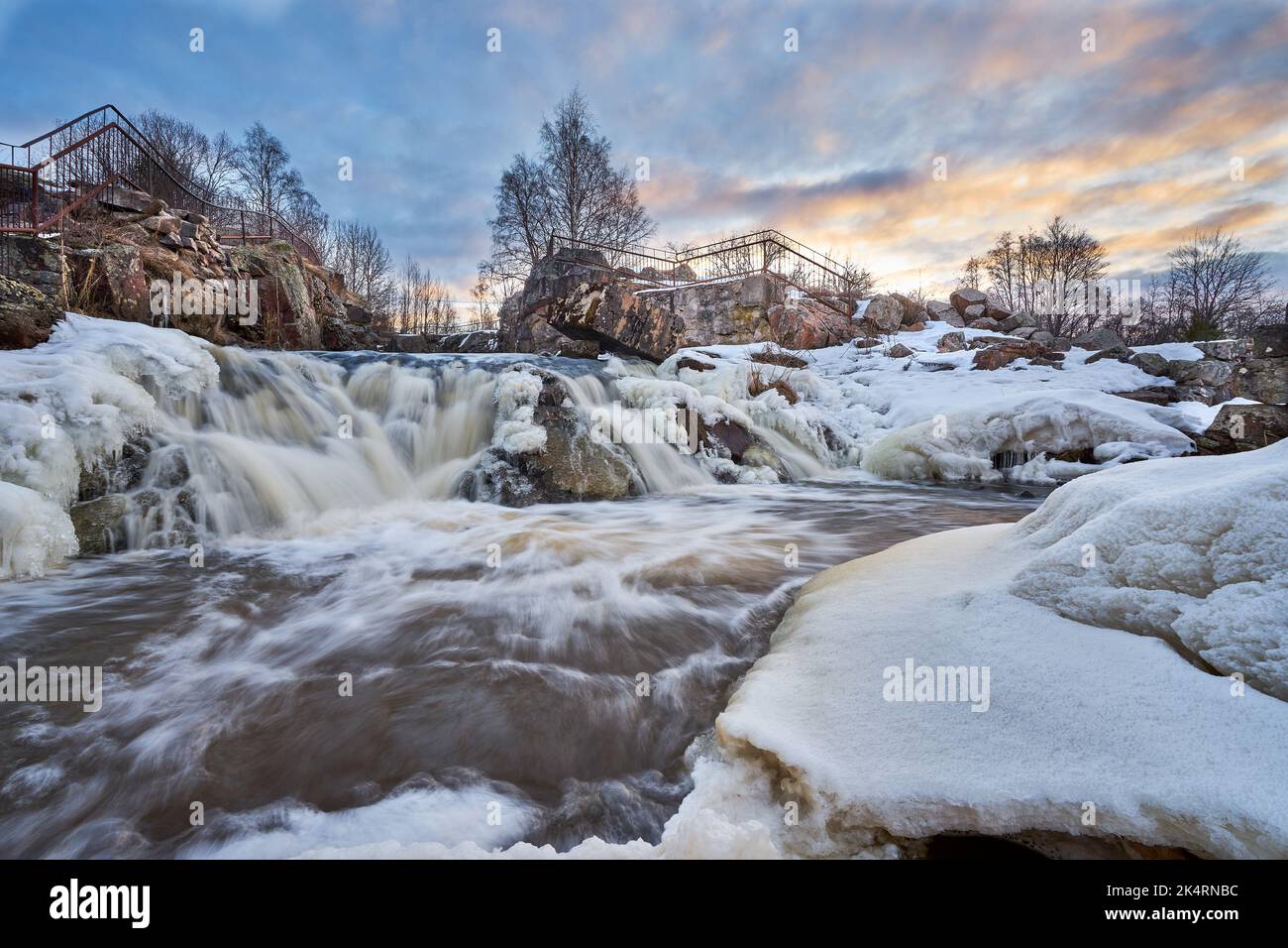 A low exposure of water flowing down the rocks covered in snow Stock ...