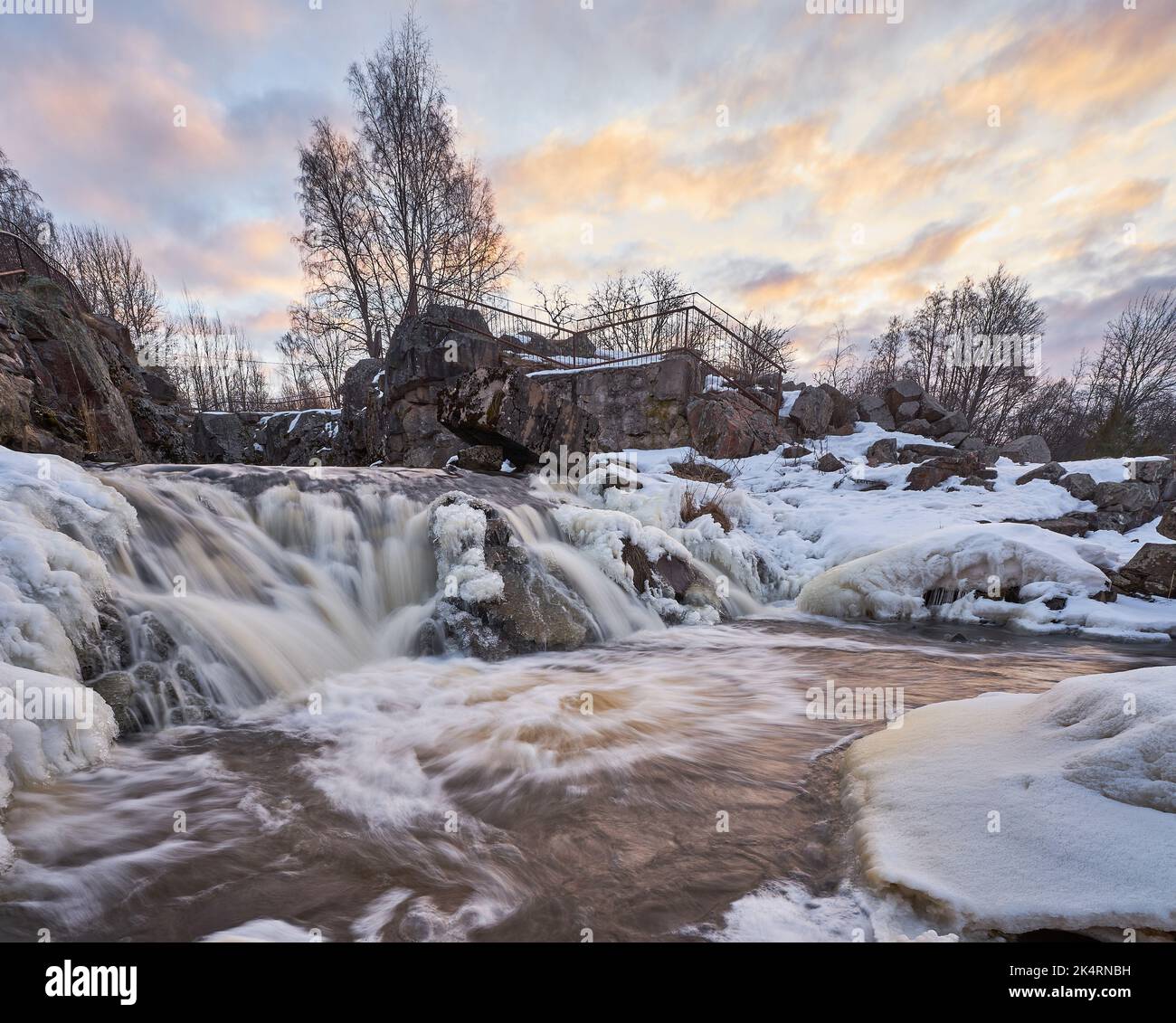 A low exposure of water flowing down the rocks covered in snow Stock ...