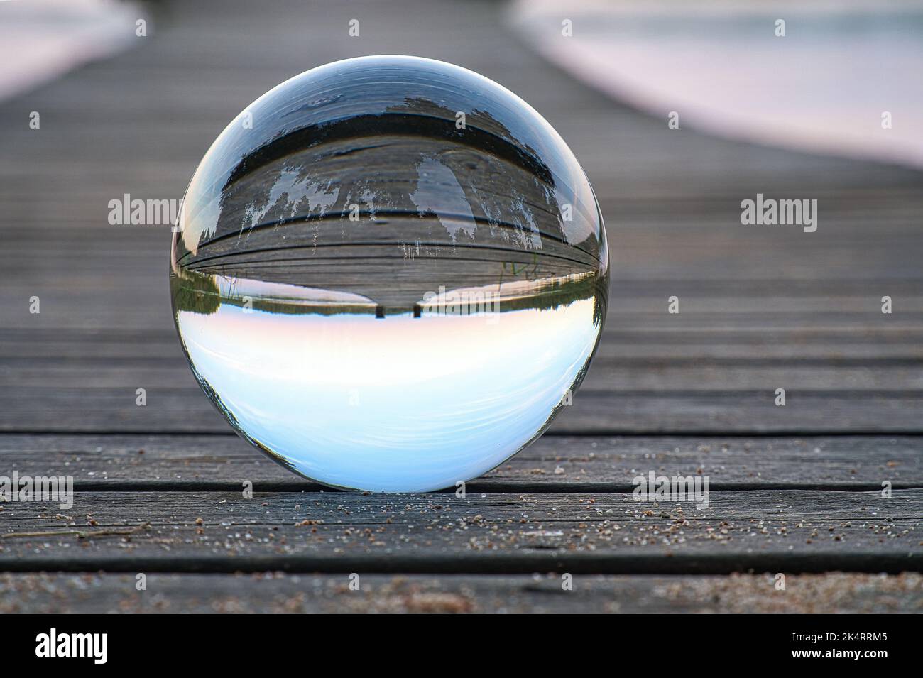 Glass ball on a wooden pier at a Swedish lake at evening hour. Nature ...