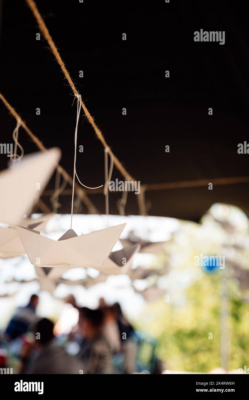 A vertical closeup shot of many paper boats hanging from the ceiling of ...