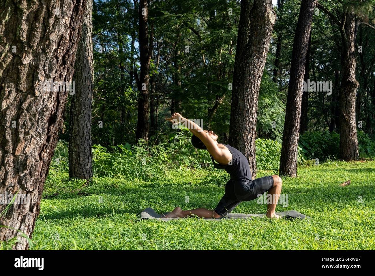 young man, doing yoga or reiki, in the forest very green vegetation, in ...