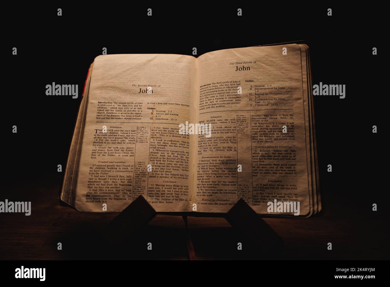 A closeup shot of a historic old Bible open on the John pages on display in a dark room Stock ...