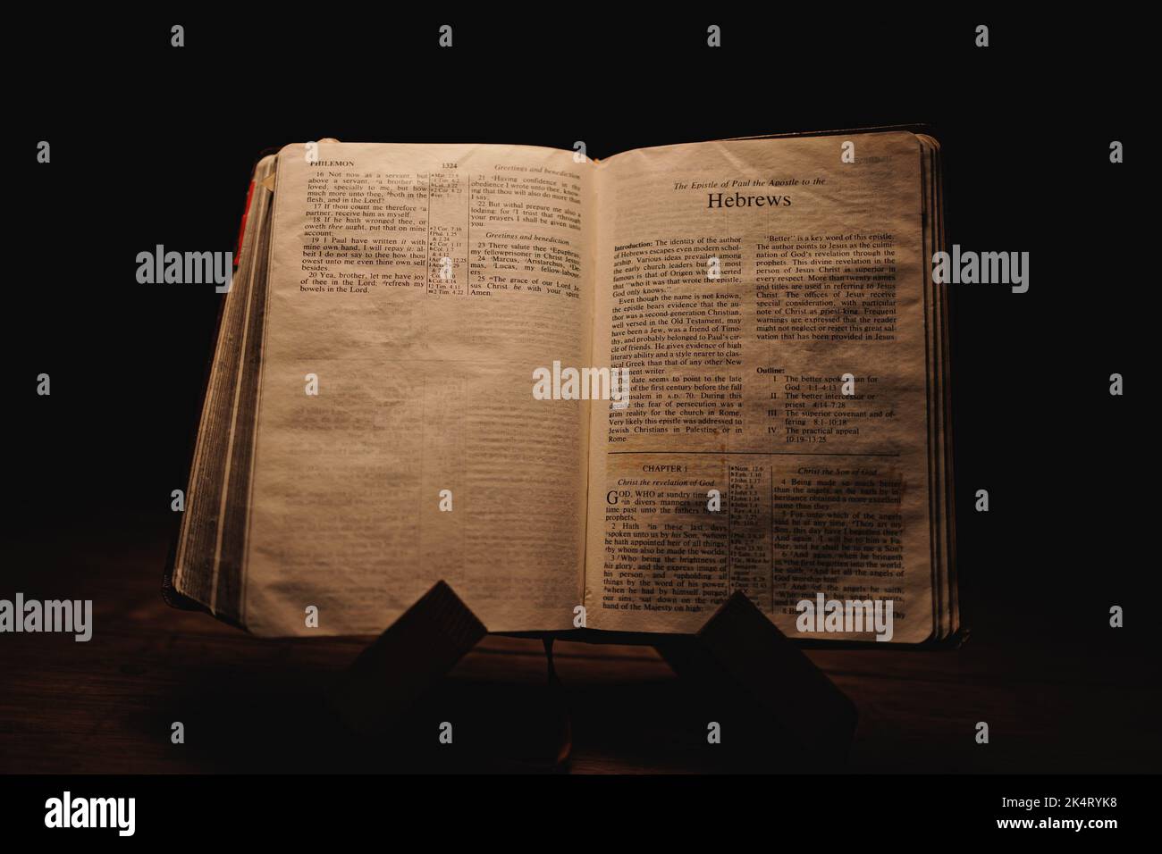 A closeup shot of a historic old Bible open on the Hebrews pages on display in a dark room Stock ...