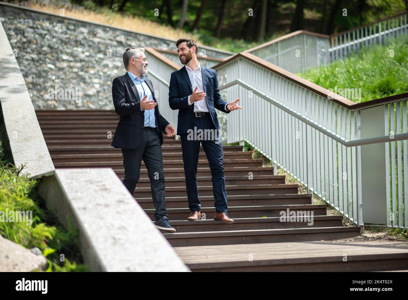 Two businessmen walking down the stairs and talking Stock Photo - Alamy