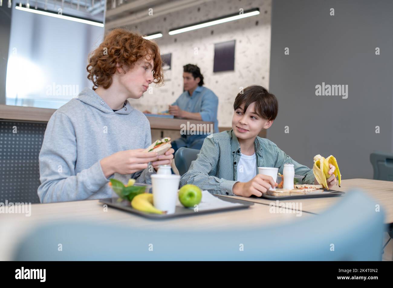 Two pupils eating lunch in the school canteen Stock Photo - Alamy