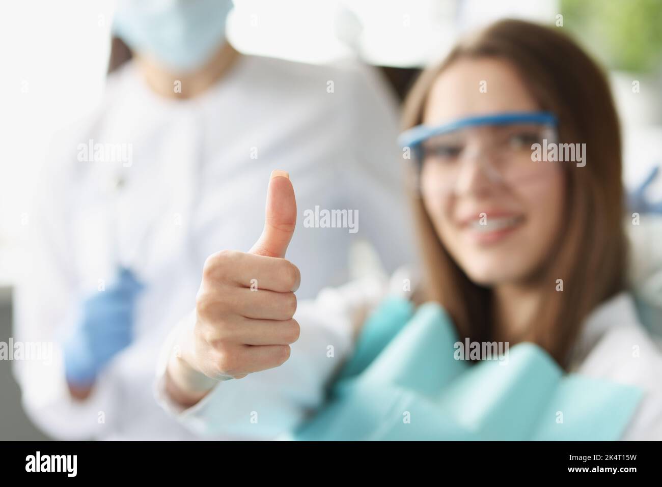A woman at the dentist shows a thumbs up gesture Stock Photo - Alamy