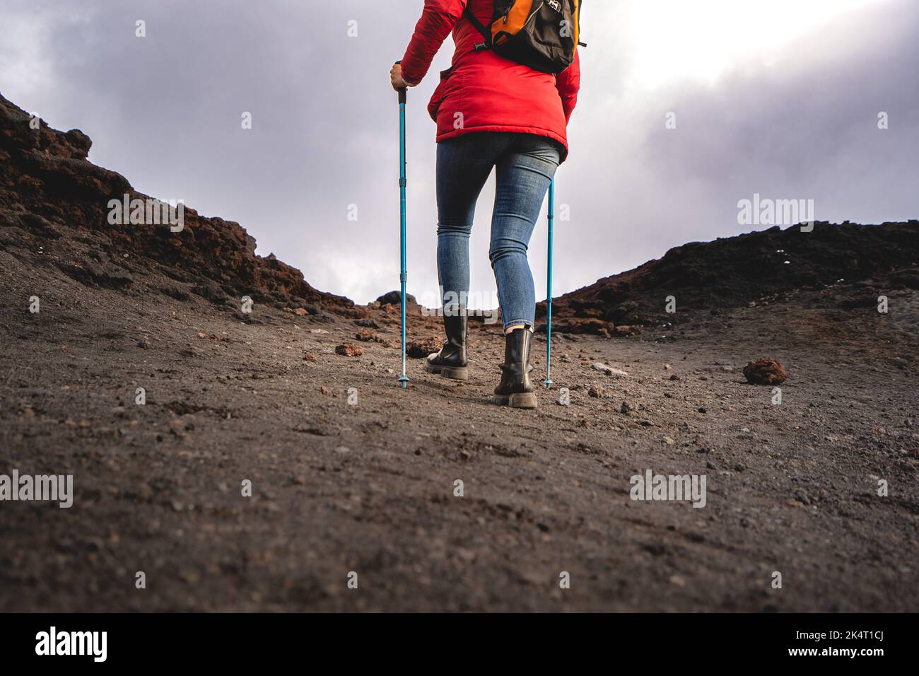 Female hiker walking on a lava stone path at the top of the volcano ...