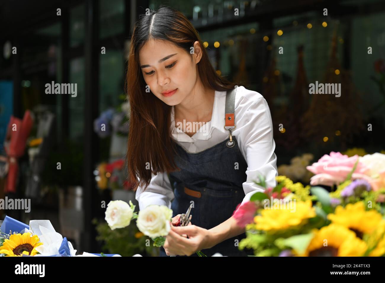 Small business owner florist wearing apron making bouquet, decorations ...
