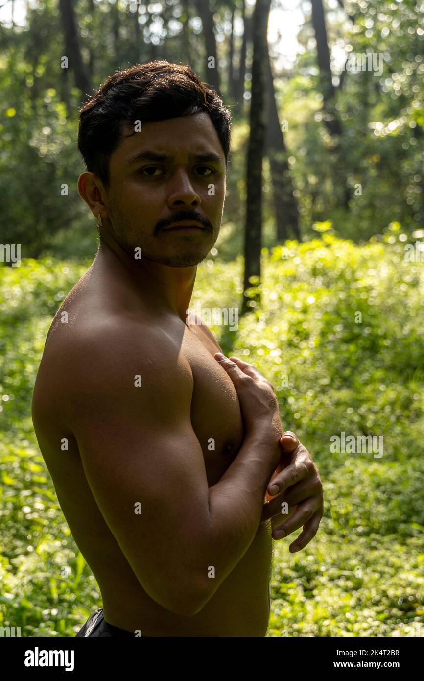 man seen up close, without shirt doing stretches on yoga mat, exercise ...