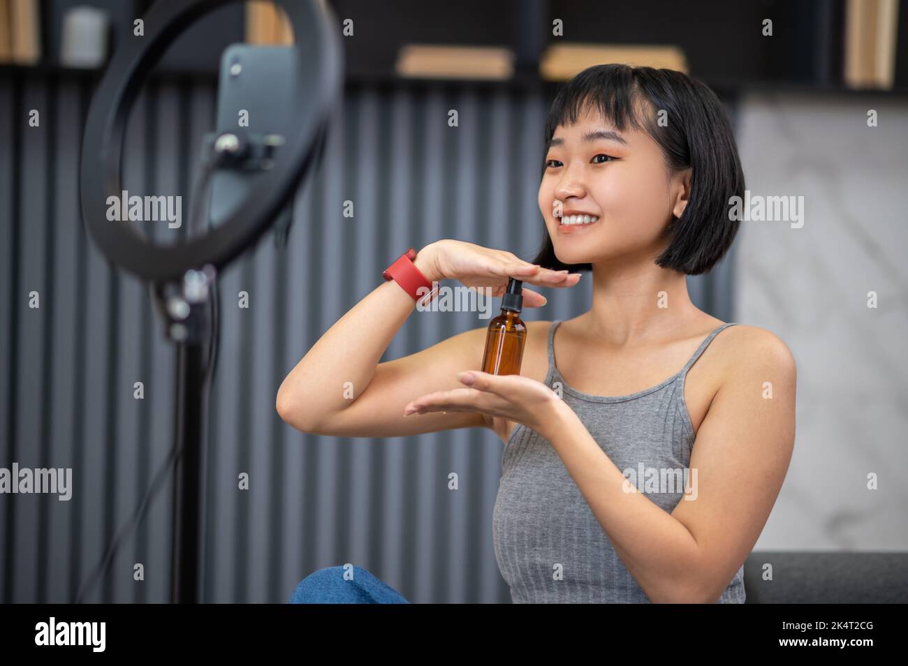 Cheerful vlogger showing a skincare product in her beauty vlog Stock ...