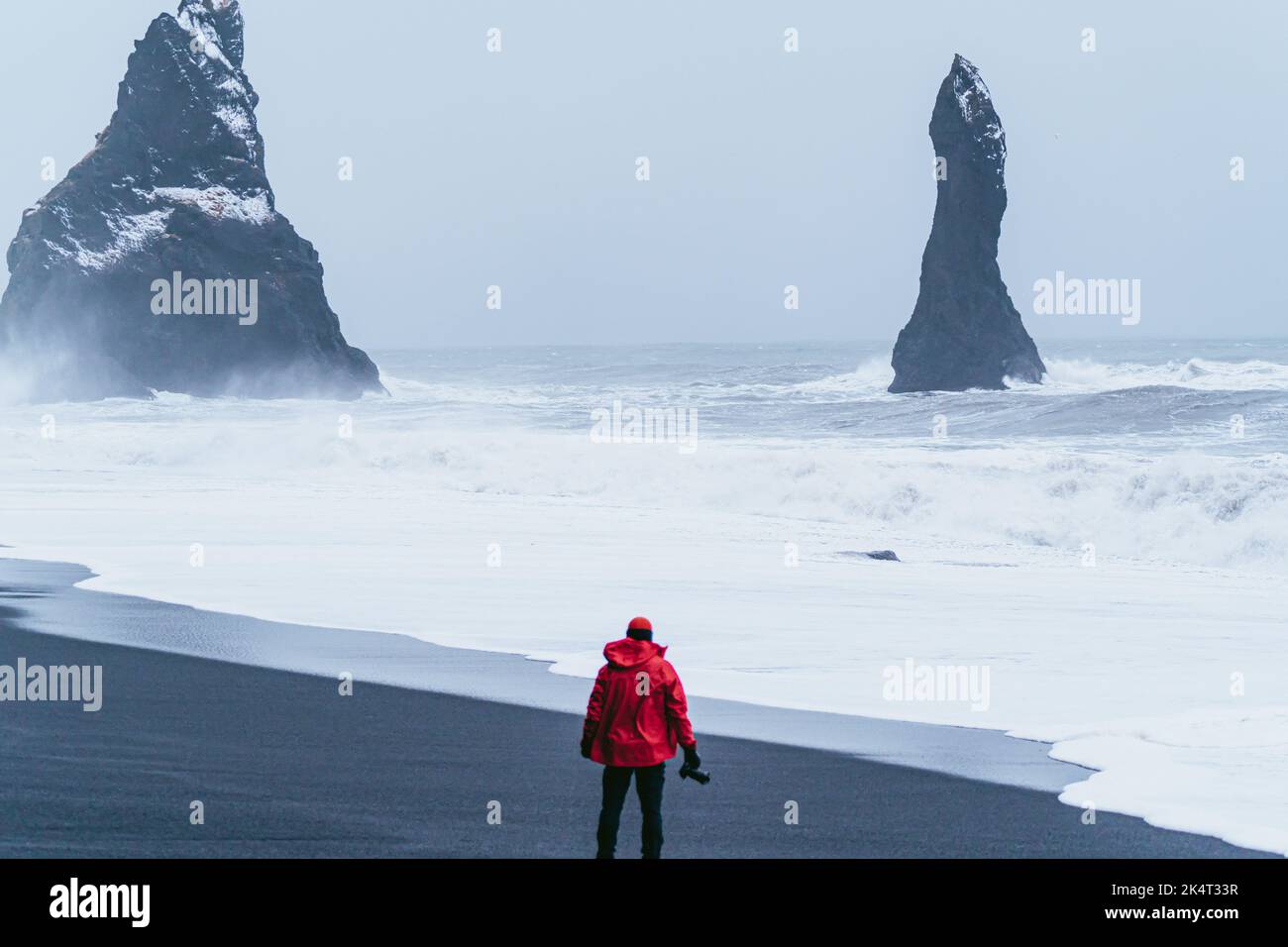 photographer man on the very cold black sand beach. Big rocks Stock ...