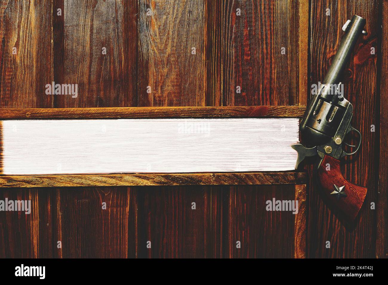Cowboy gun revolver on a light brown wooden wall . Space for text. Boss ...
