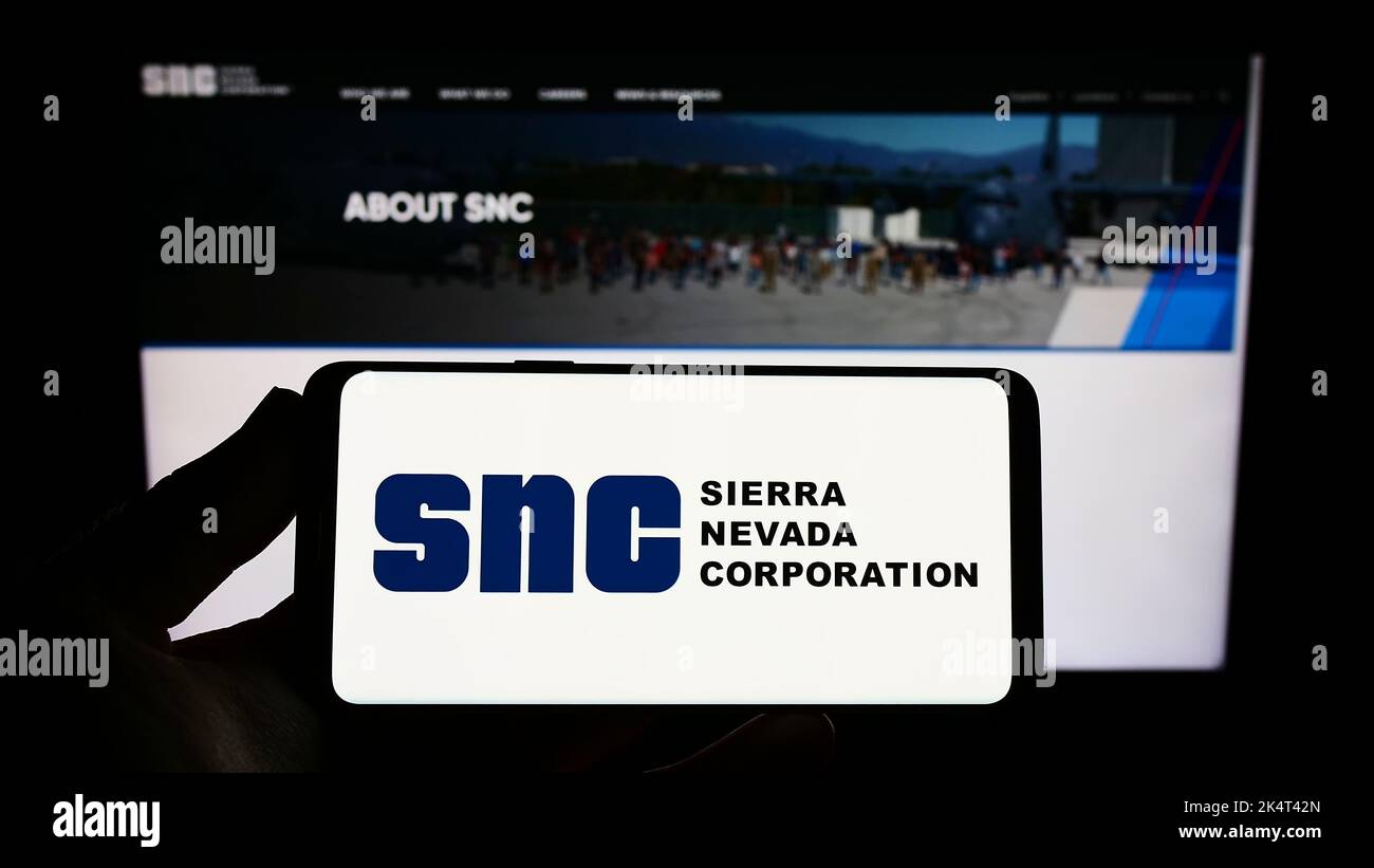 Person holding smartphone with logo of aerospace company Sierra Nevada ...