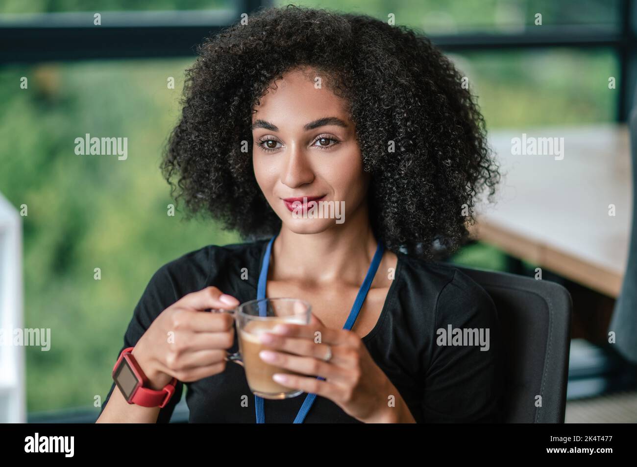 Cute brunette woman looking contented while sitting in the office and ...