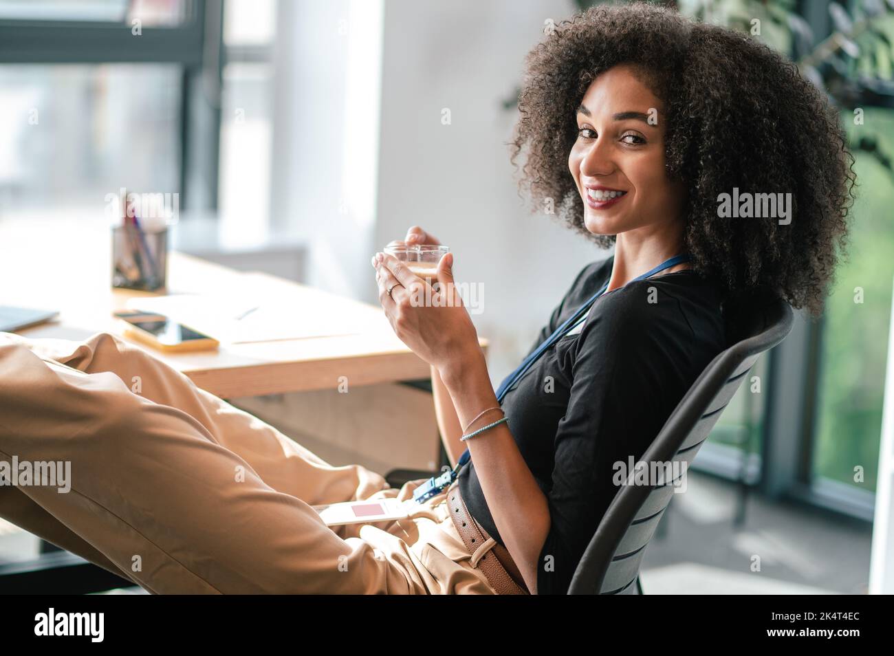 Cute brunette woman looking contented while sitting in the office and ...