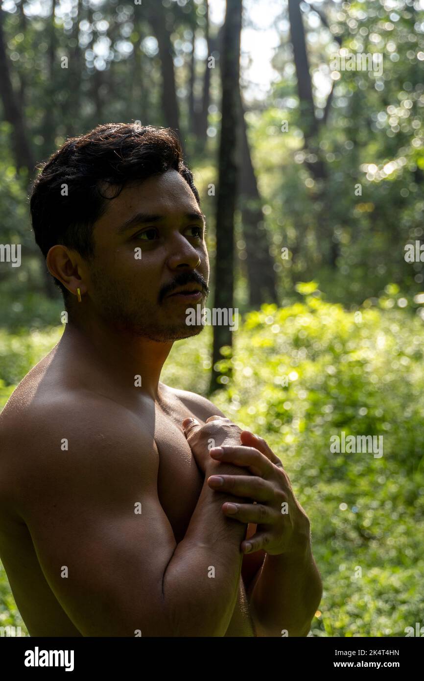 man seen up close, without shirt doing stretches on yoga mat, exercise ...