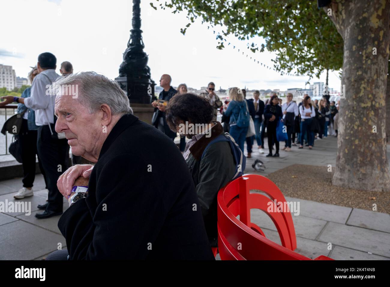 Man takes a sit down rest as long queues of people on the Southbank ...
