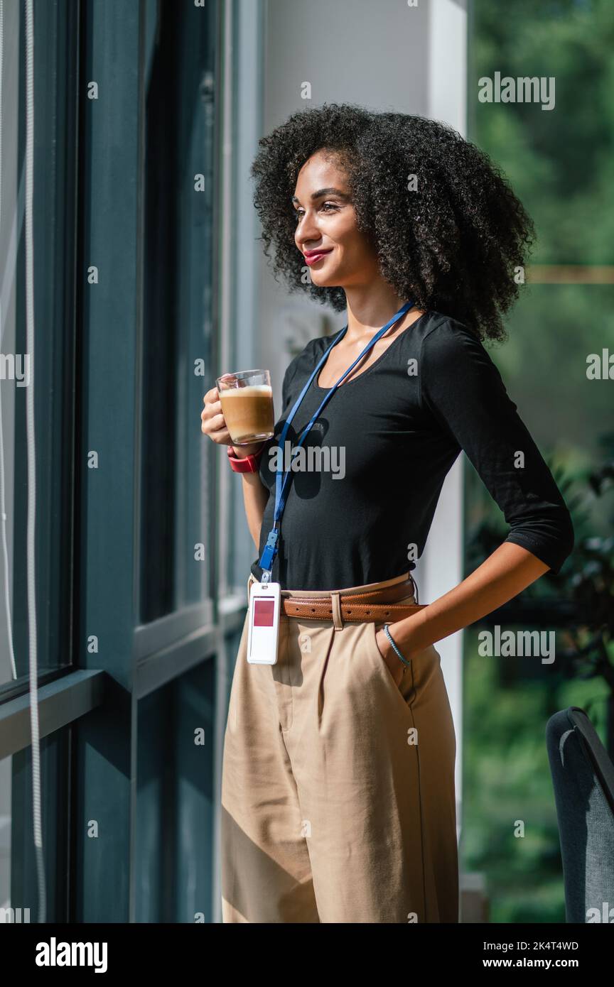 Elegant beautiful curly-haired woman at the window in the office Stock ...