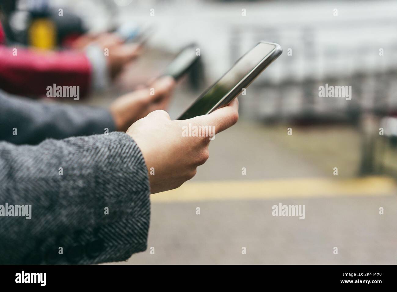 Young people using mobile phones outdoor - Focus on left hand holding ...