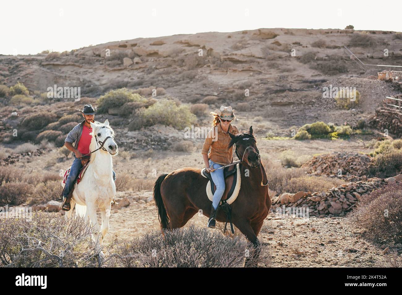 Young couple riding horses doing excursion at sunset - Focus on woman ...