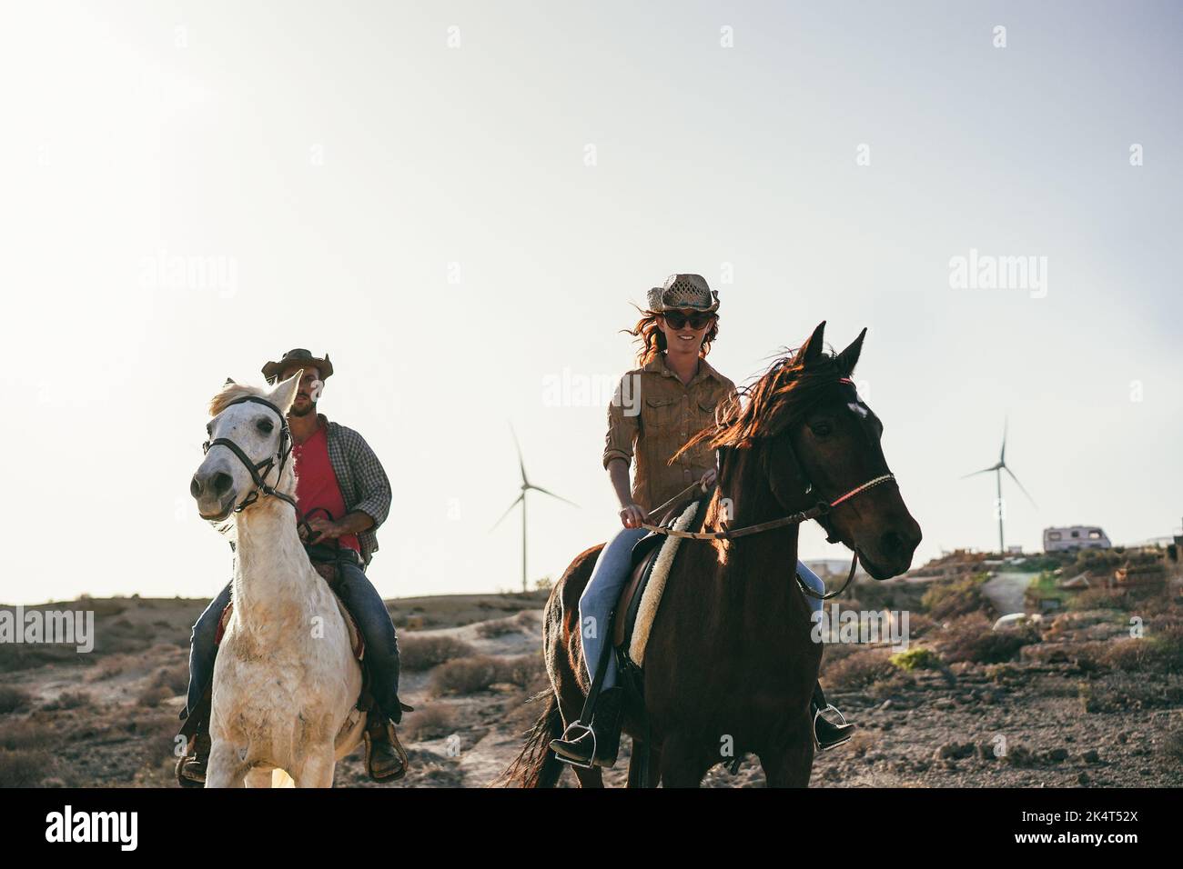 Young couple riding horses doing excursion at sunset - Soft focus on ...