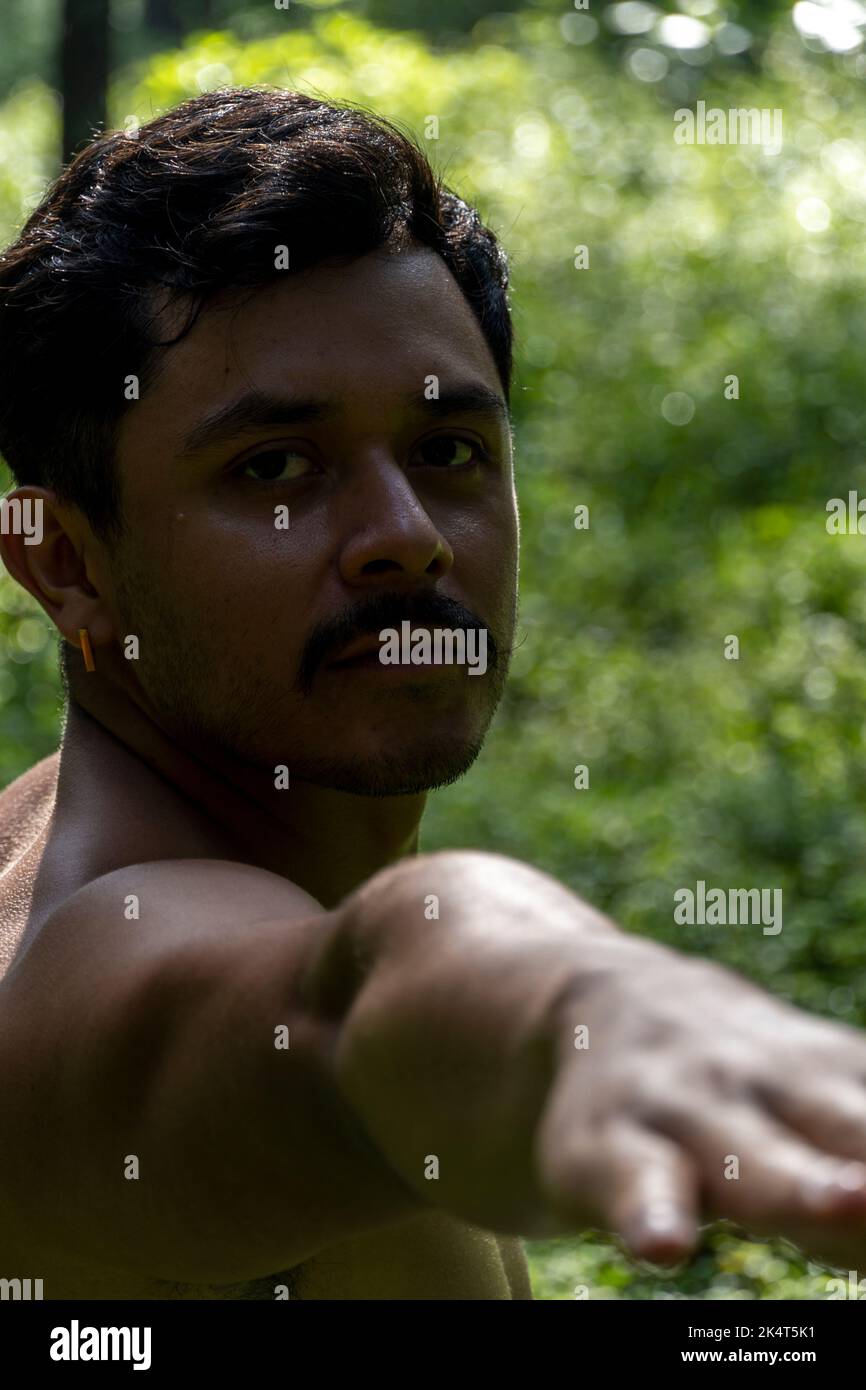 man seen up close, without shirt doing stretches on yoga mat, exercise ...