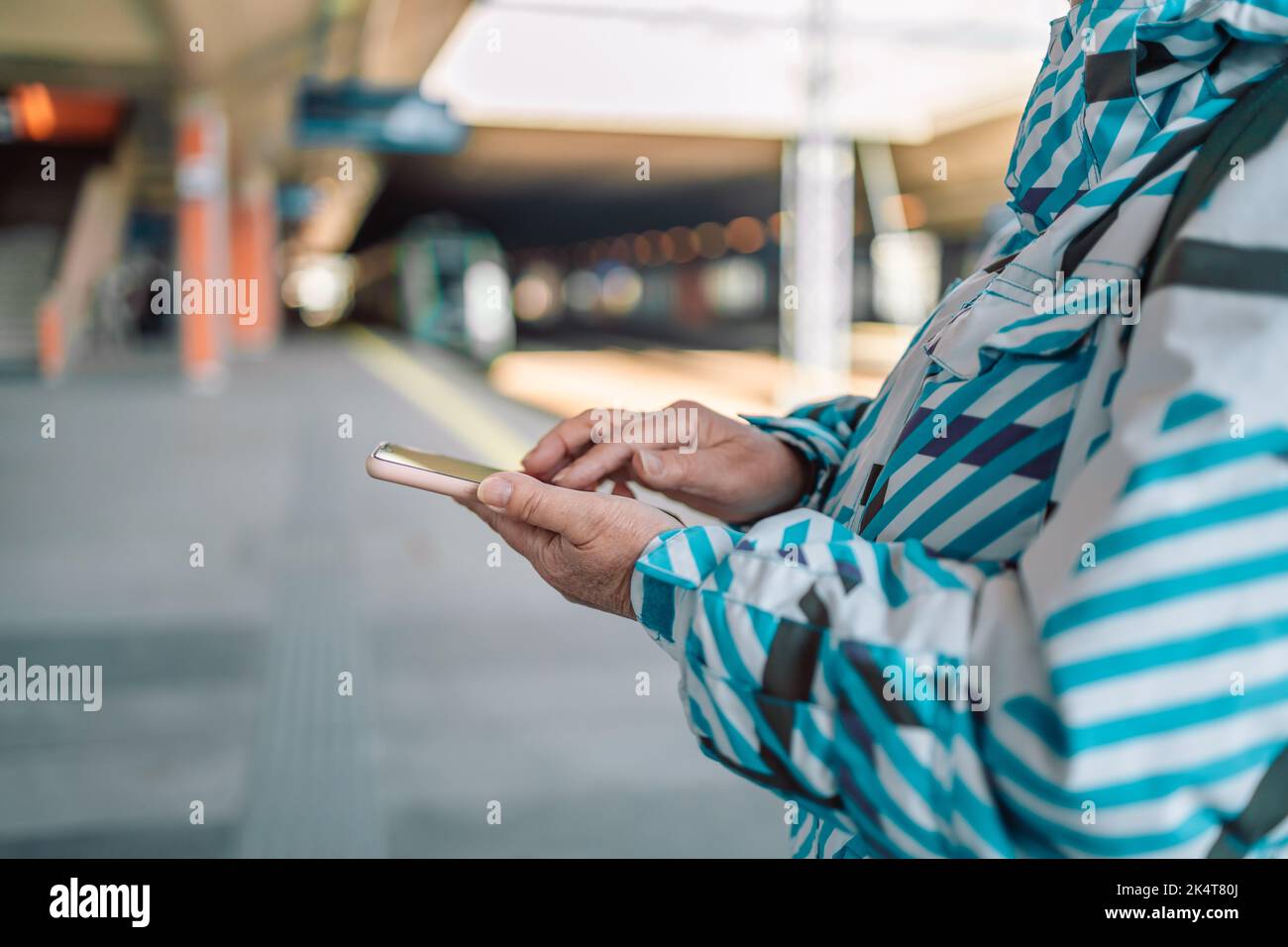 Close up of woman hands typing phone on train station platform on ...