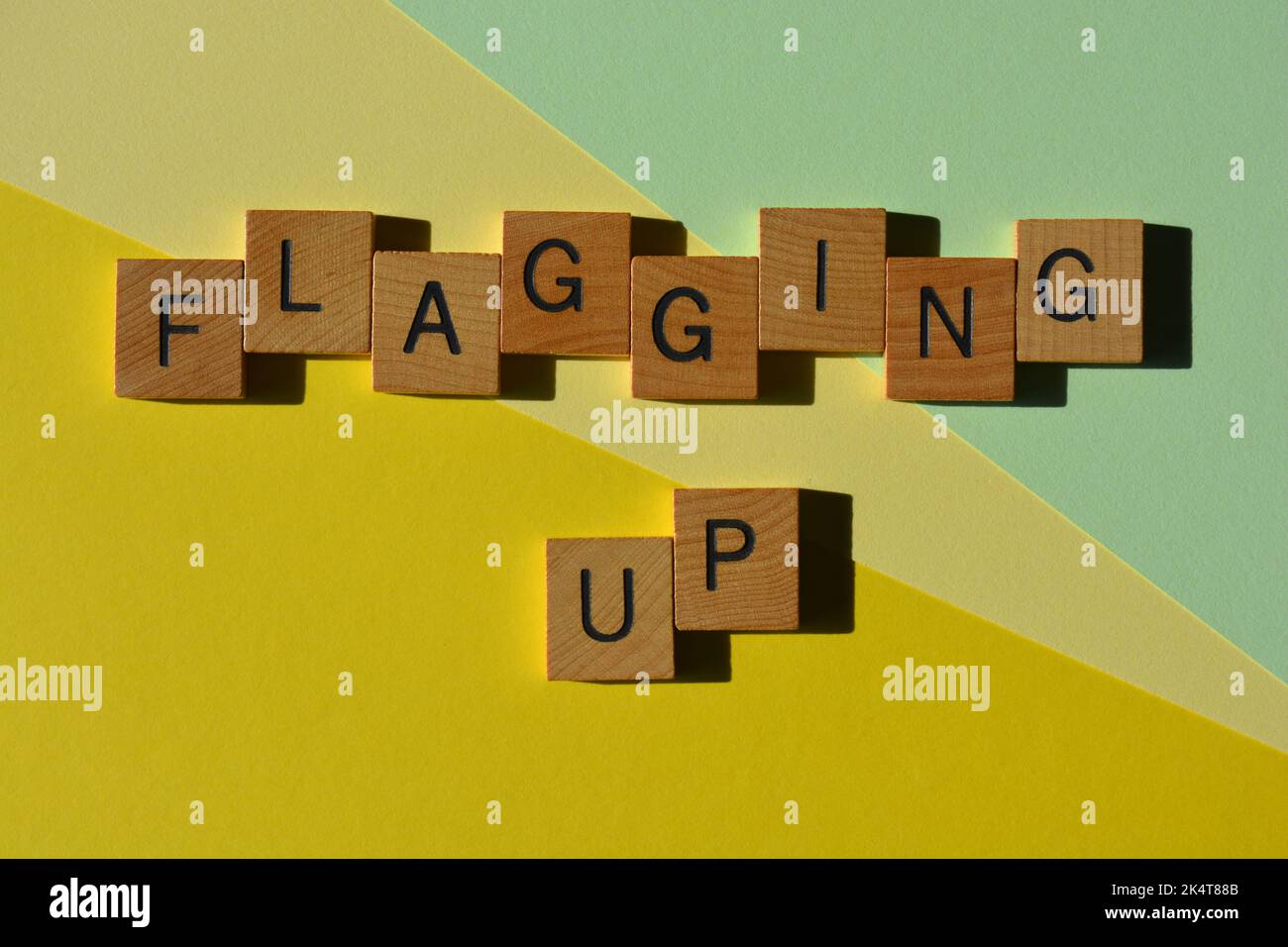 Flagging Up, words in wooden alphabet letters isolated on yellow and ...