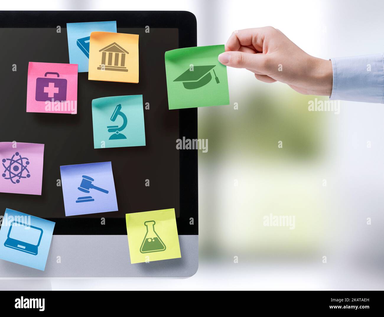 Hand sticking notes with educational subjects icons on a computer ...