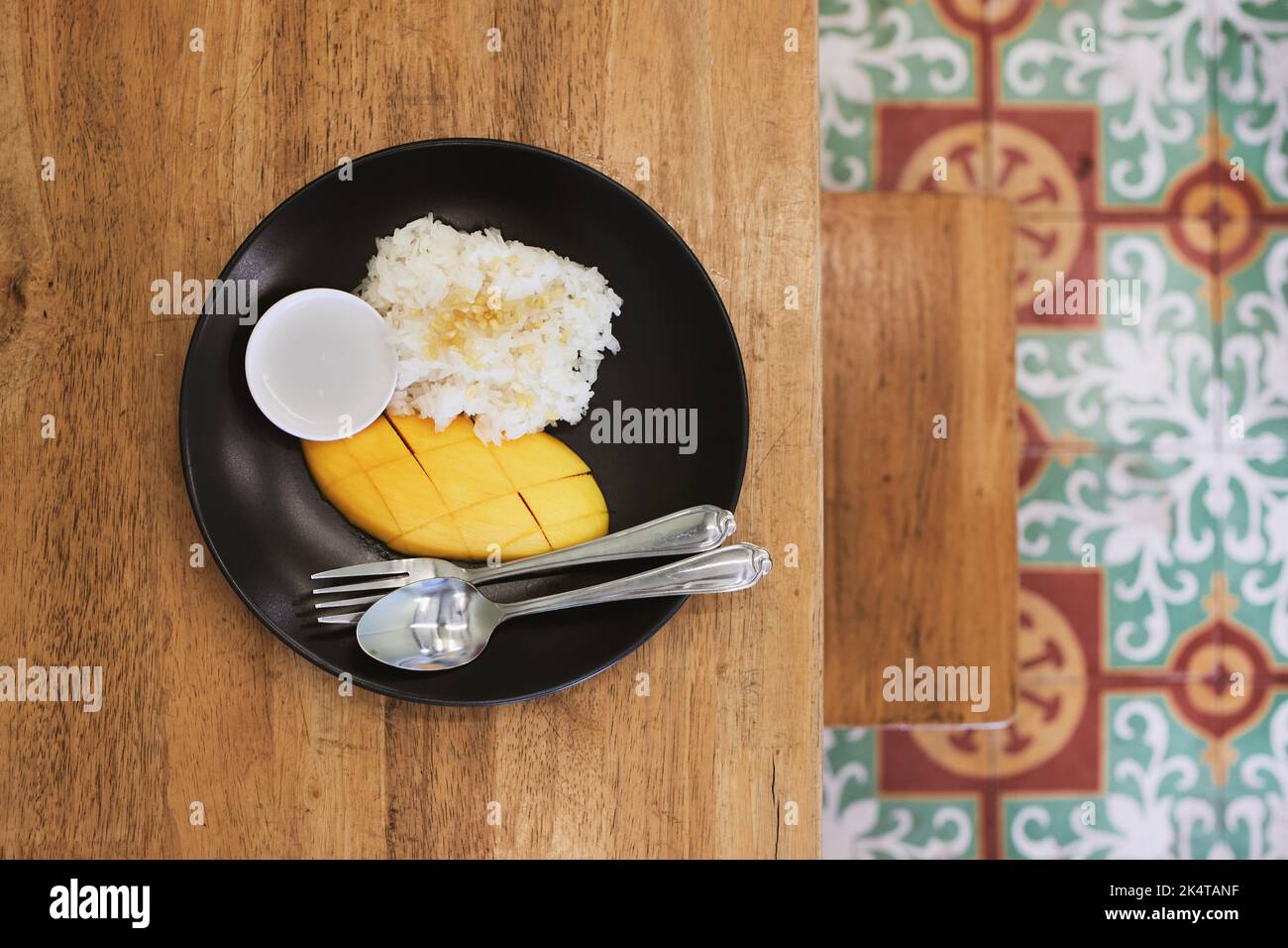 Fresh mango with sticky rice and sweetened coconut milk on wooden table ...