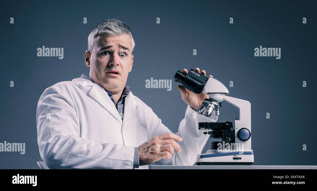 Funny shocked medical scientist working with a microscope, he made an ...