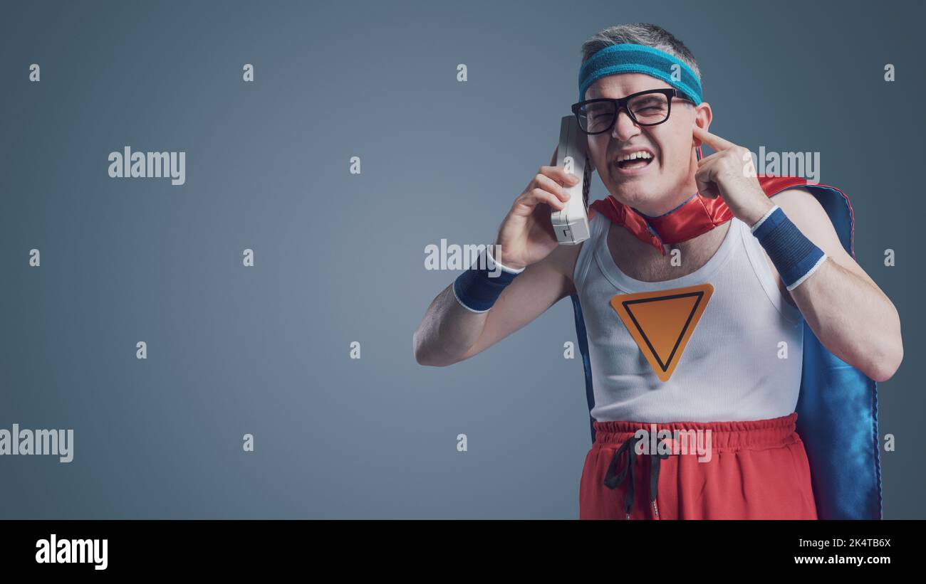 Funny superhero making a phone call using an old obsolete cordless ...