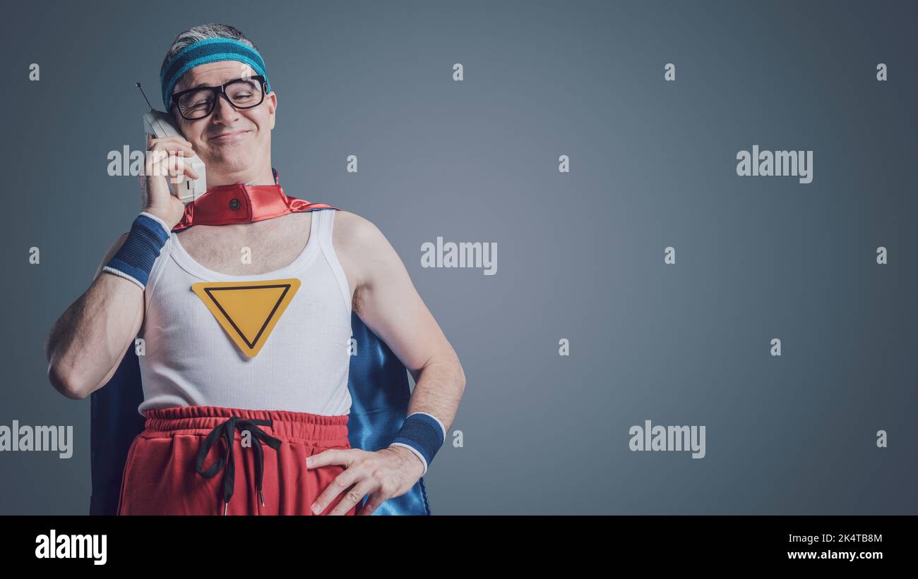 Funny confident superhero making a phone call using an old obsolete ...