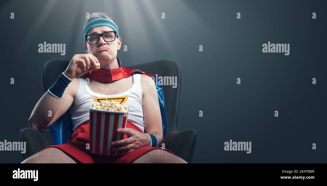 Funny superhero watching a boring movie and eating popcorn, he is sad ...