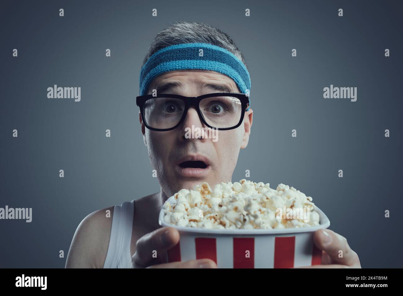 Funny guy with glasses and headband watching movies, he is staring at ...