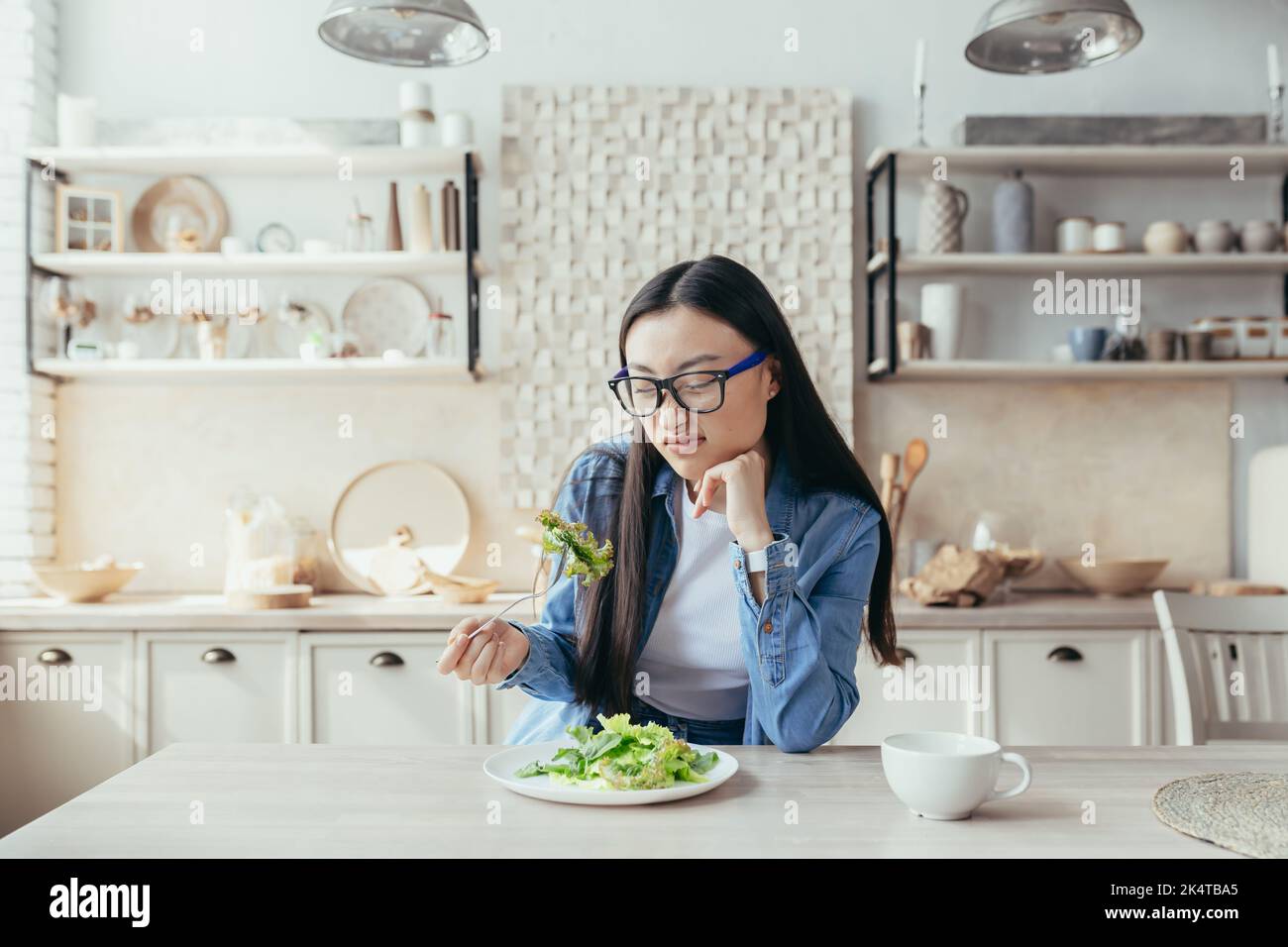 Young asian woman unhappy with diet in kitchen, woman eating healthy ...