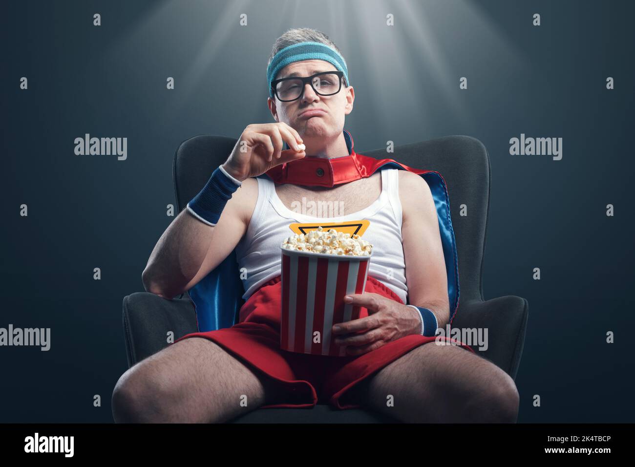 Funny superhero watching a boring movie and eating popcorn, he is sad ...
