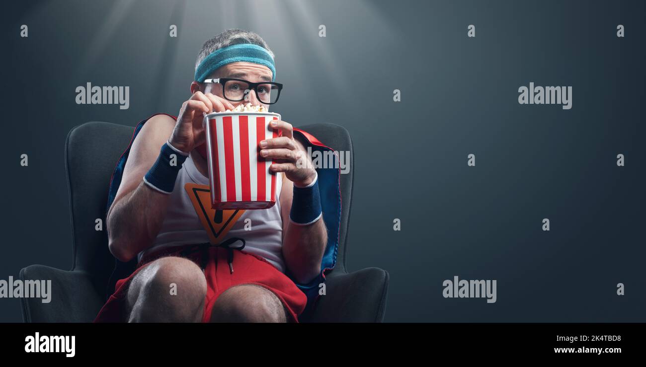 Funny superhero watching horror movies and eating popcorn, he is ...