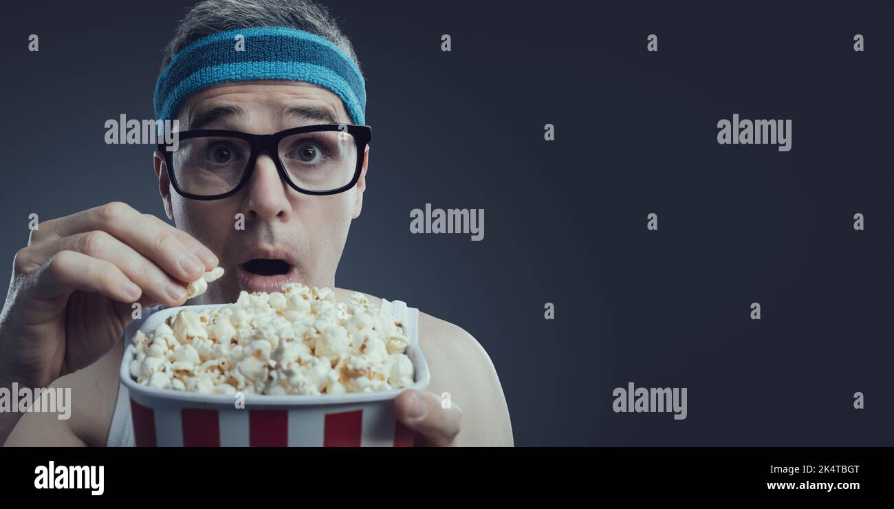 Funny guy with glasses and headband watching movies, he is staring at ...