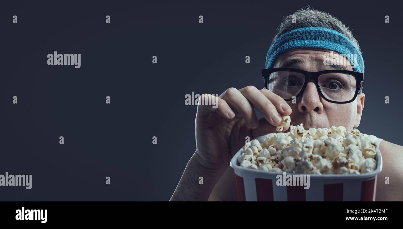 Funny scared guy watching horror movies and eating popcorn, blank copy ...