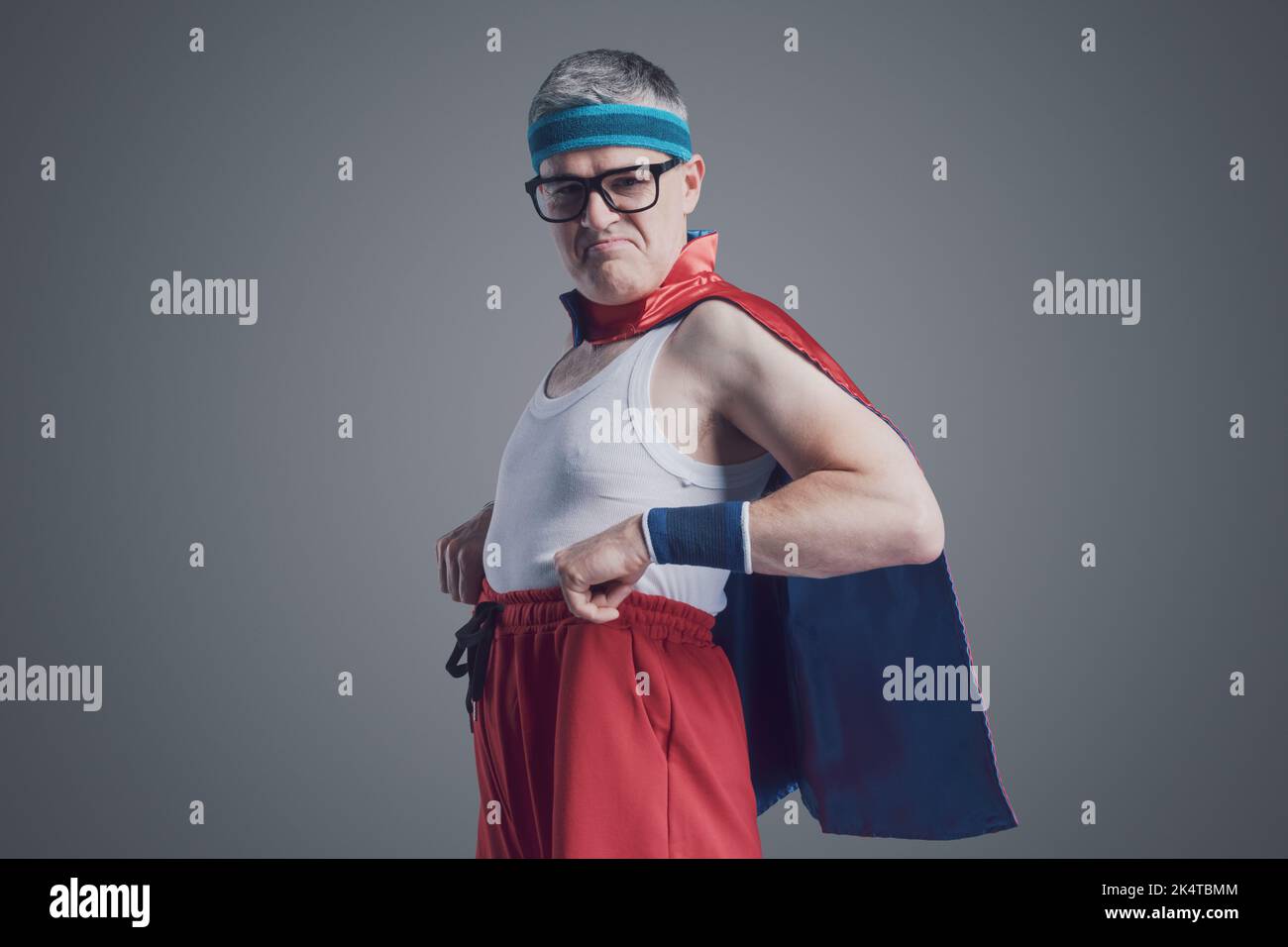 Funny confident superhero looking at camera and pulling his shorts ...