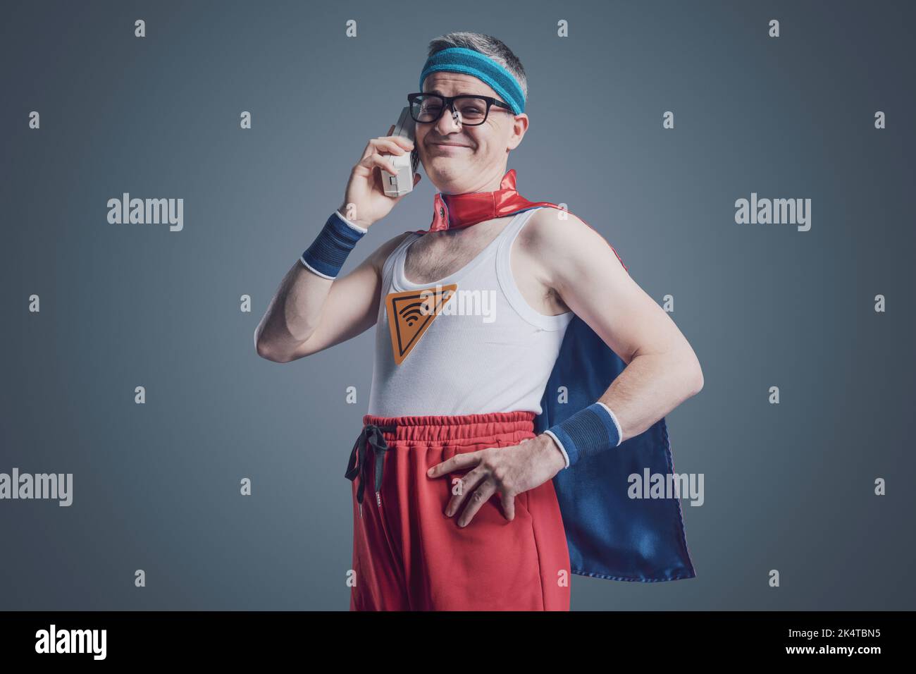 Funny confident superhero making a phone call using an old obsolete ...