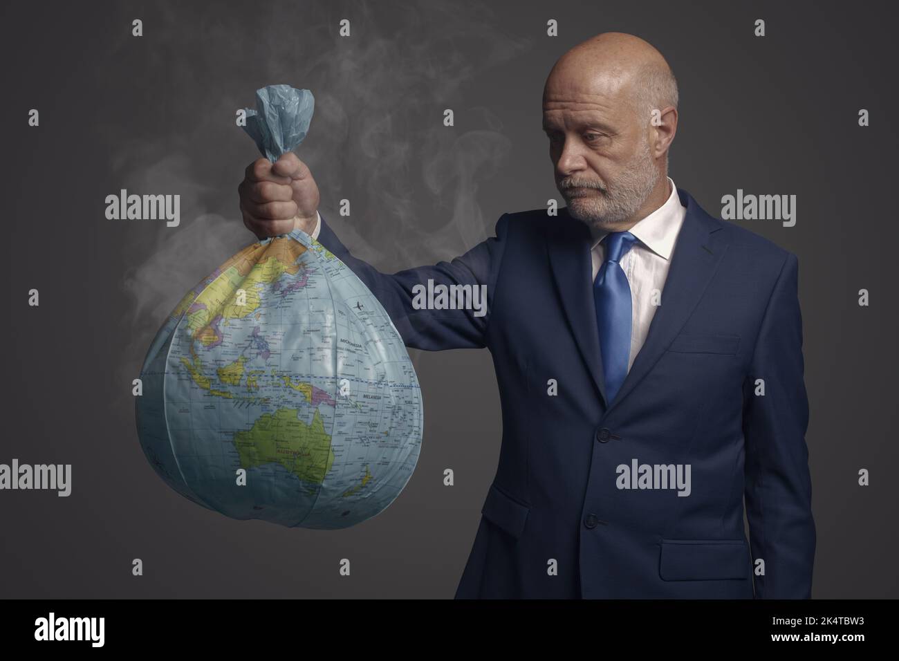 Corporate businessman holding a polluted smelly earth, the globe is ...
