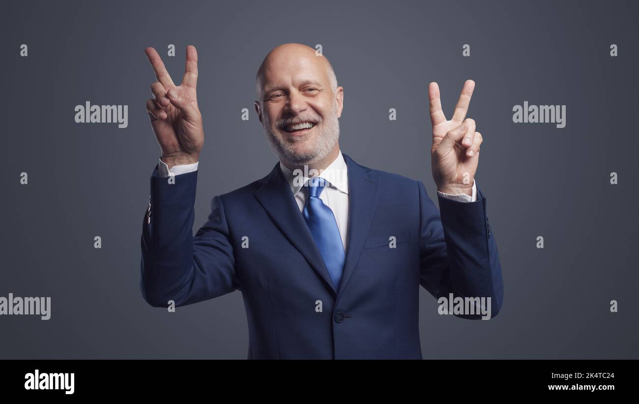 Cheerful happy businessman making a V sign and smiling, successful ...