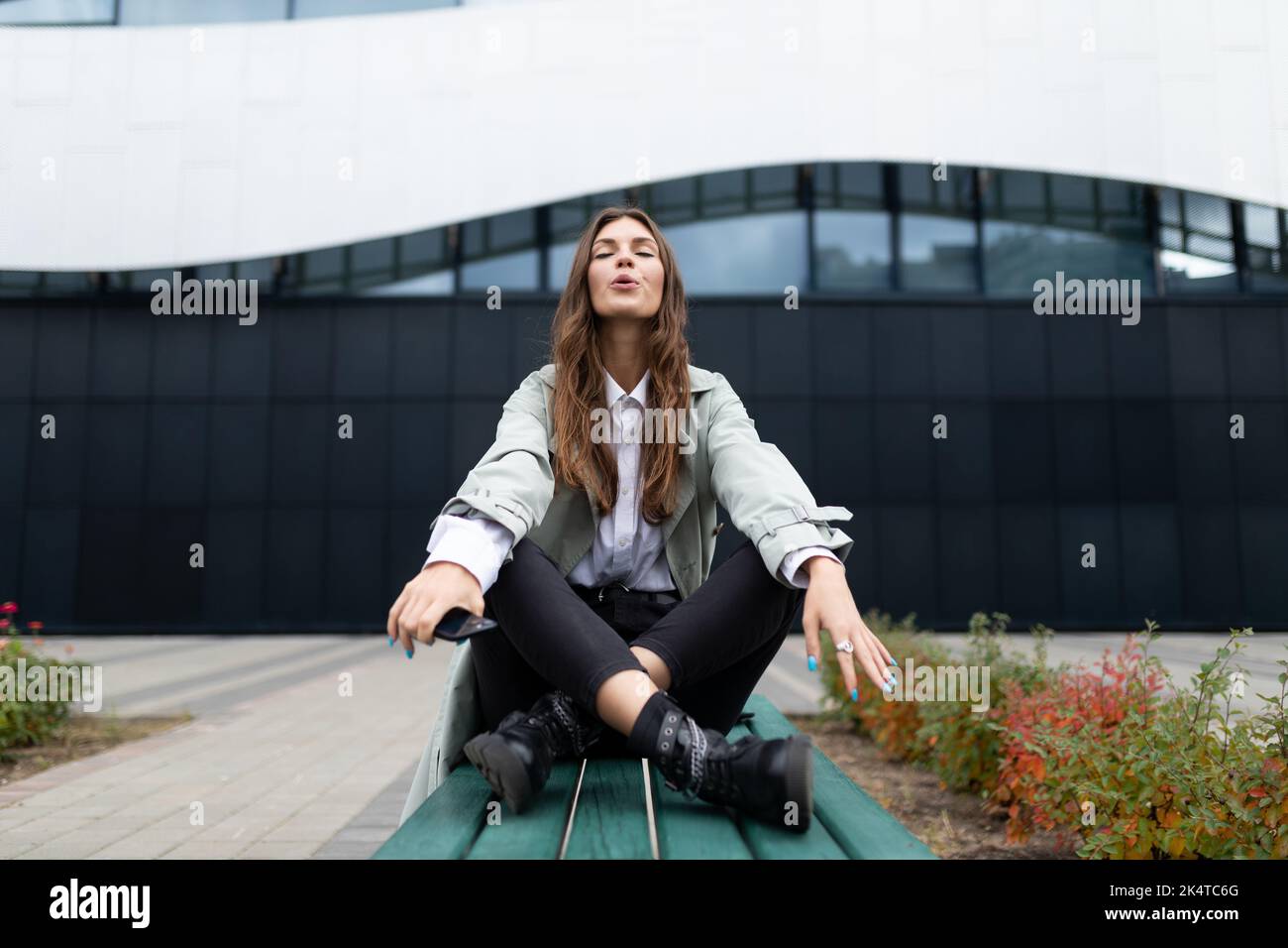 young woman sitting in yoga pose in park resting during work break near ...